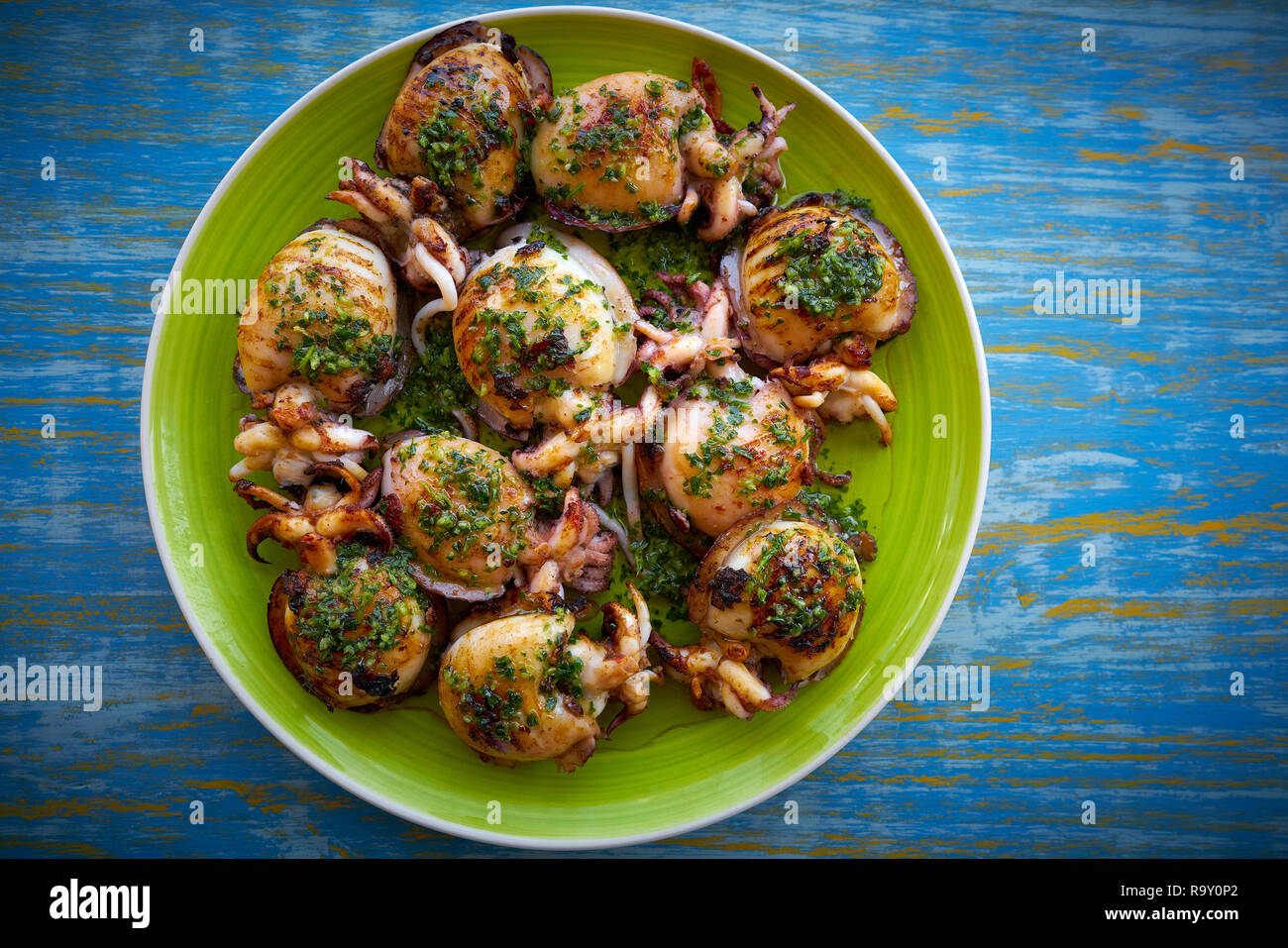Grilled cuttlefish squid with parsley sauce and garlic lemon on green ...