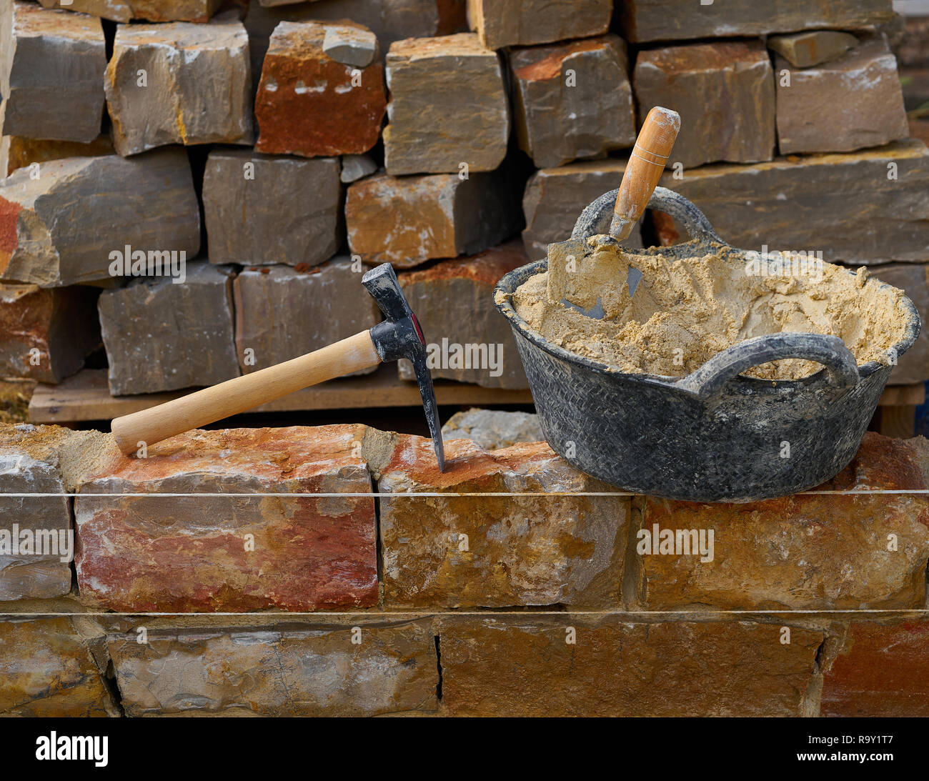 Masonry stone wall construction with mortar and brick hammer trowel ...