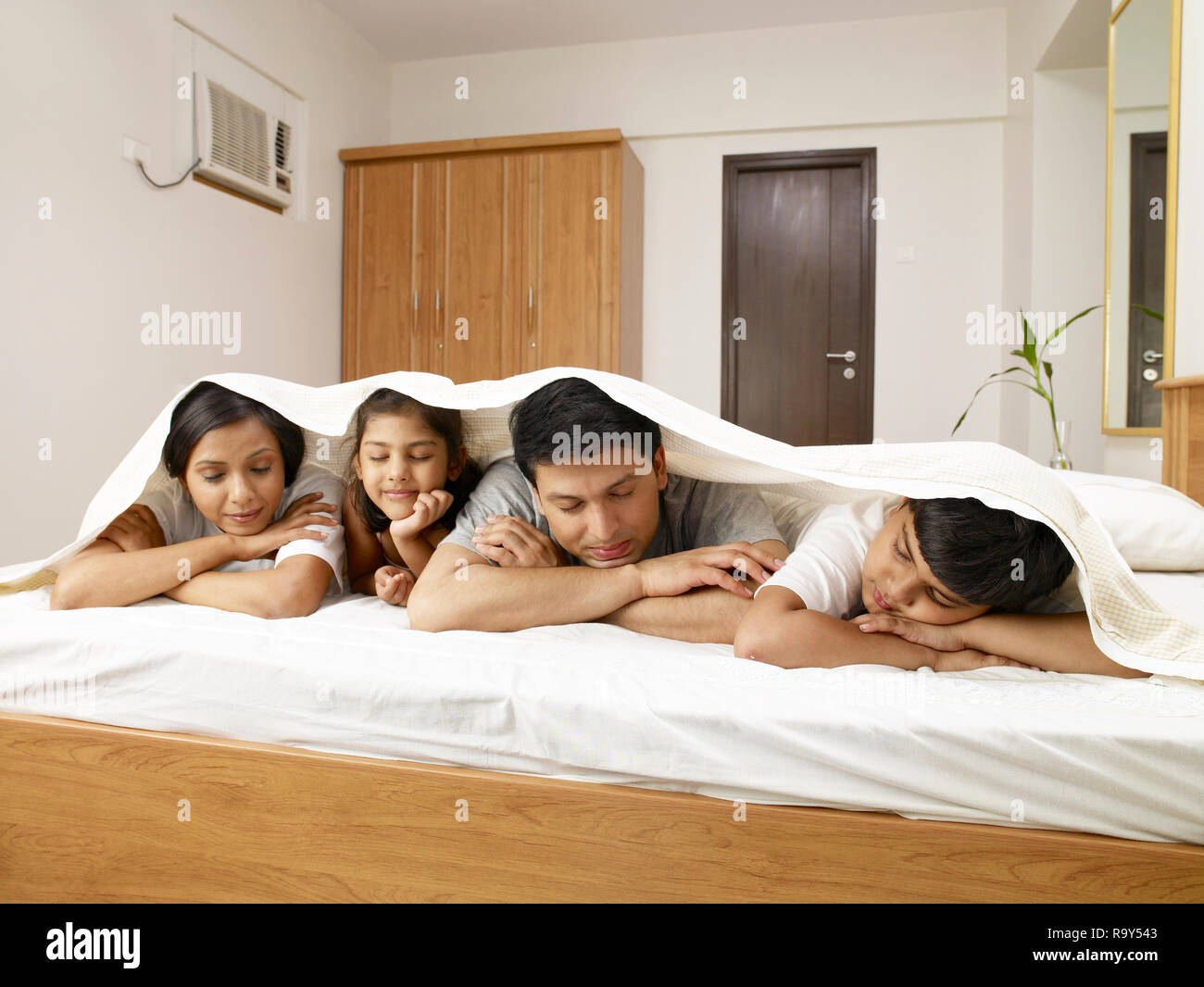 FAMILY OF FOUR DRESSED IN NIGHT CLOTHES taking a nap Stock Photo - Alamy
