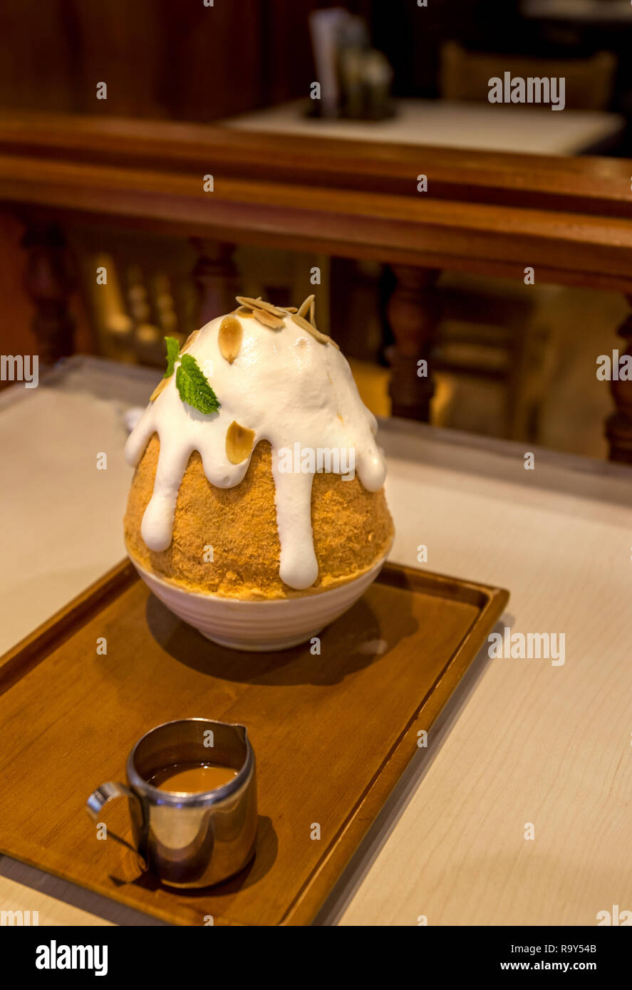 A chocolate icy volcano with white sugar toppings set on a table with a ...