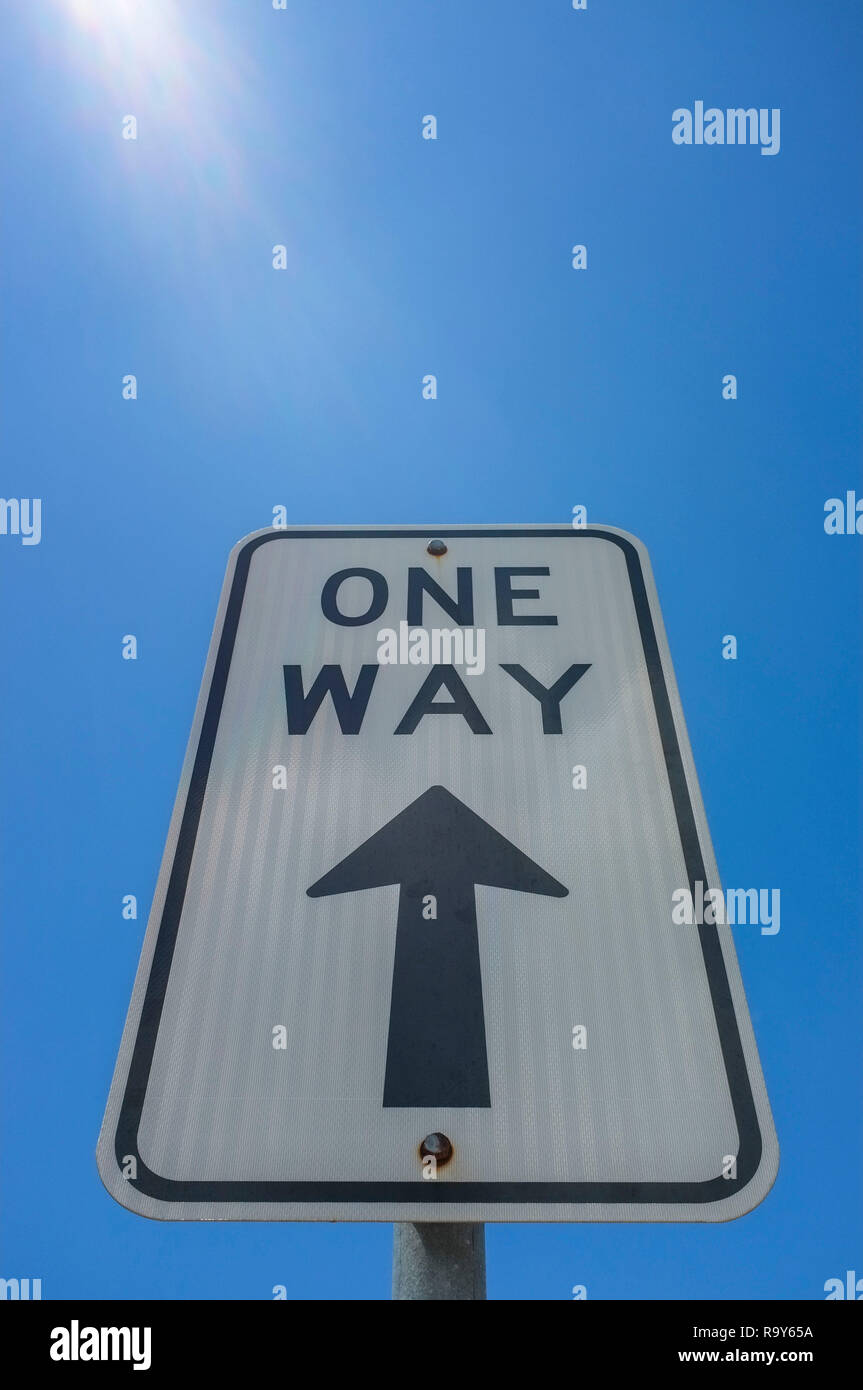One Way sign pointing toward a blue sky, with sun flare Stock Photo - Alamy