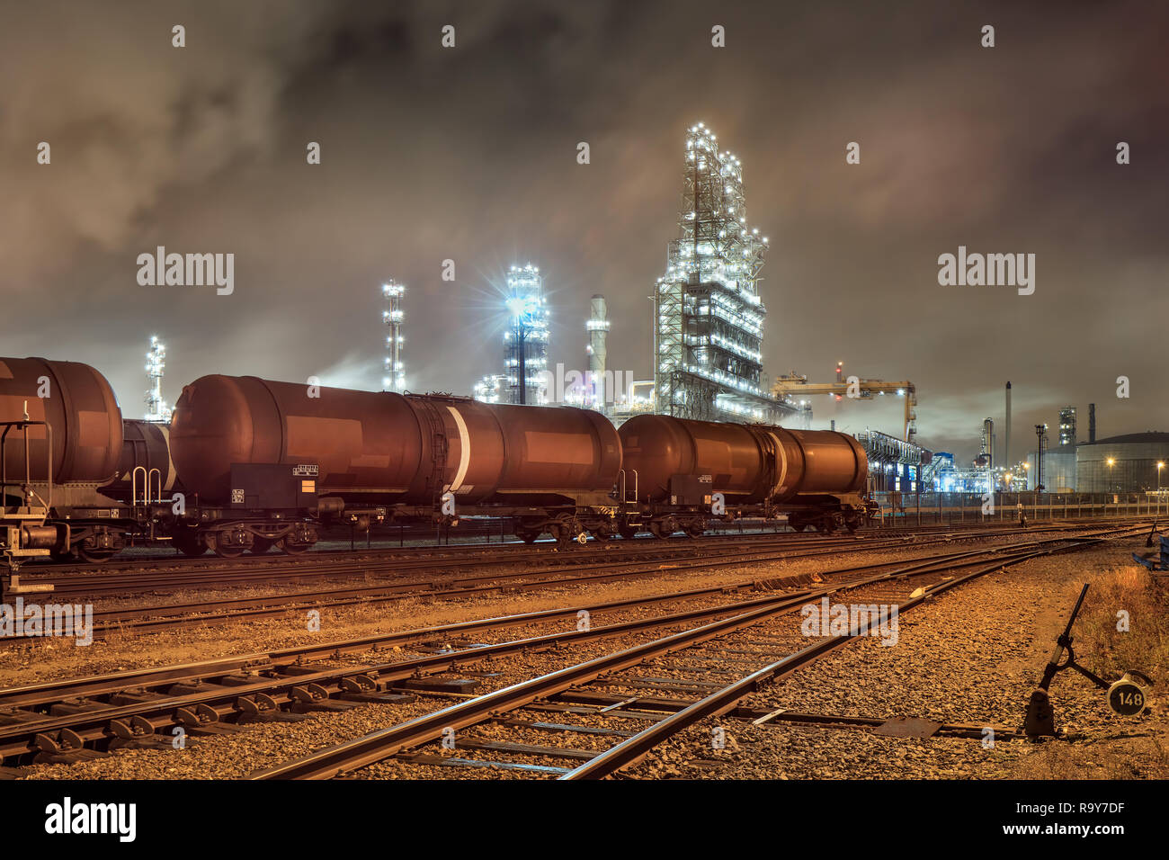 Row of train wagons with an illuminated oil refinery in Port of Antwerp ...