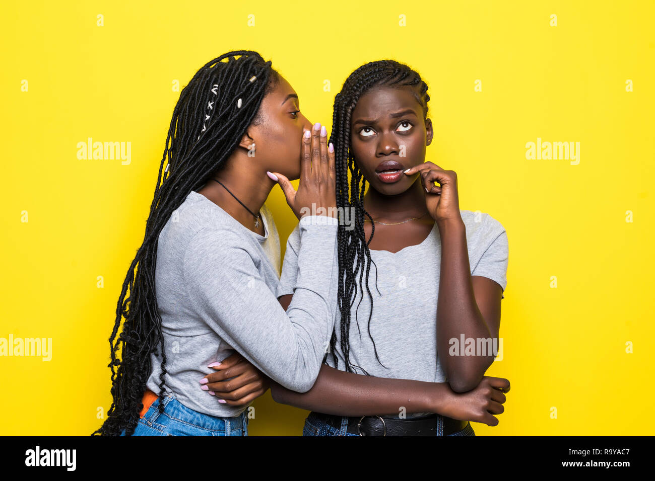 Portrait of two young african women sharing secrets isolated over ...