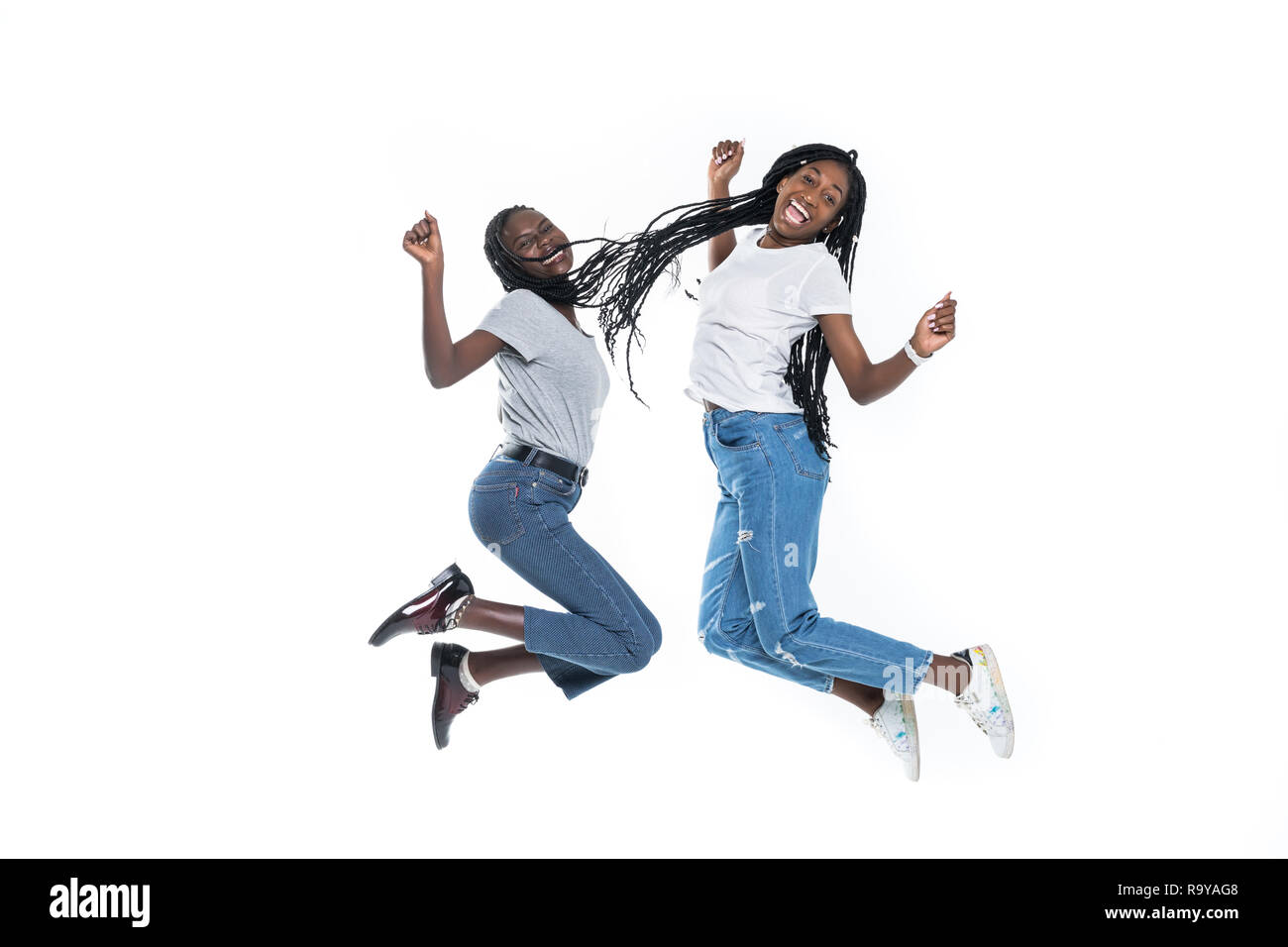 Two african girls jumping over white background Stock Photo - Alamy