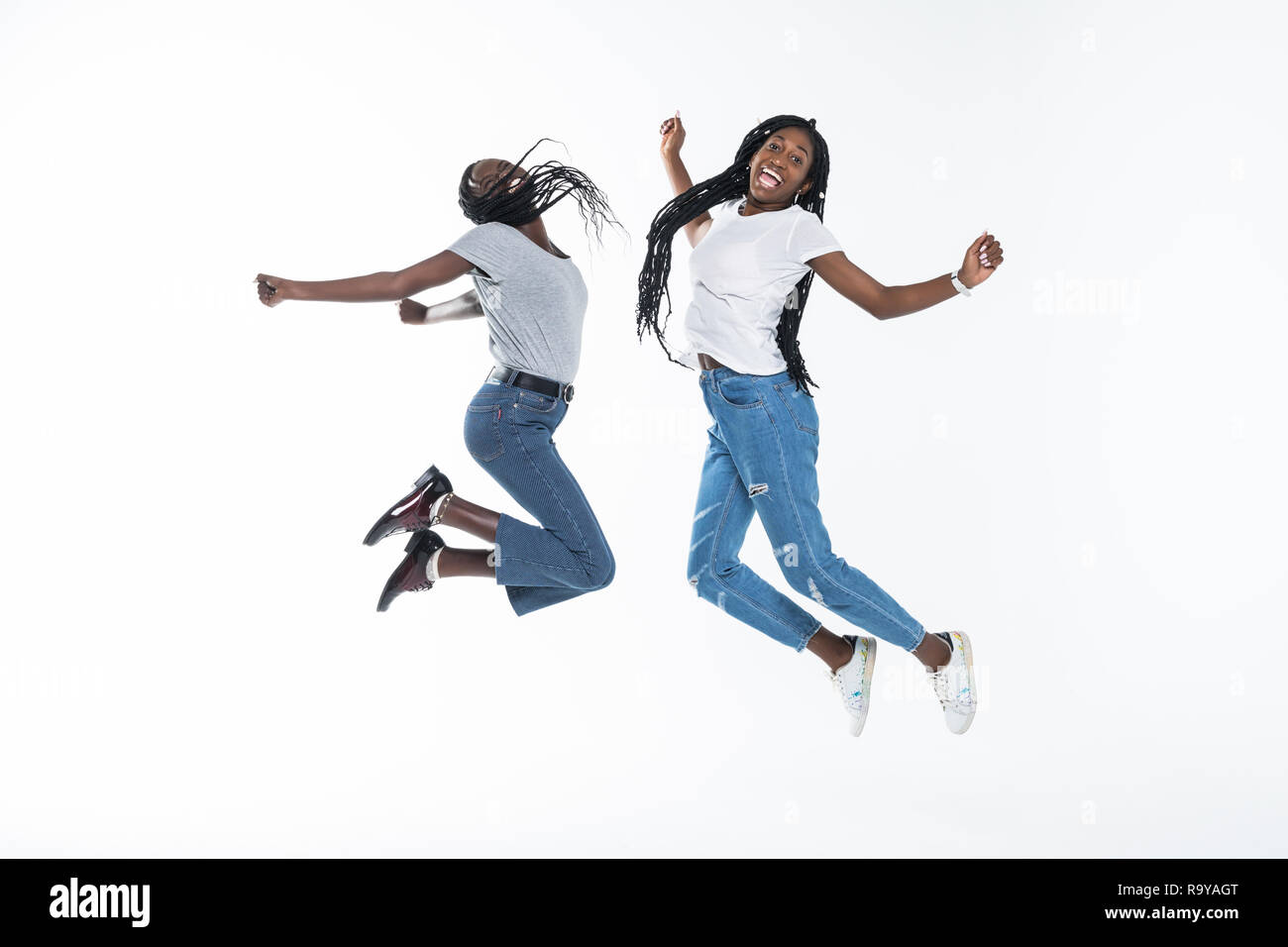 Two african girls jumping over white background Stock Photo - Alamy