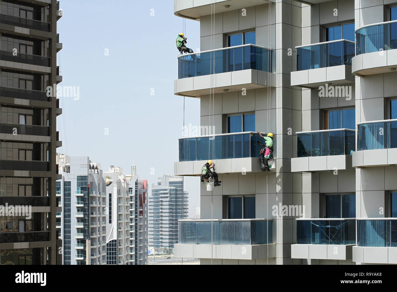Three high-rise workers wash windows of a high-rise building in Dubai ...