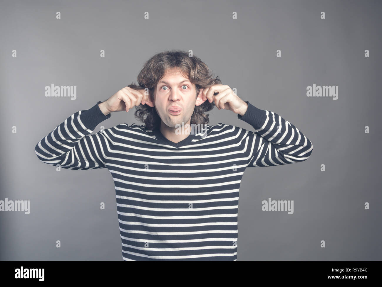 Man making silly monkey face isolated on grey background. Guy grimaces ...