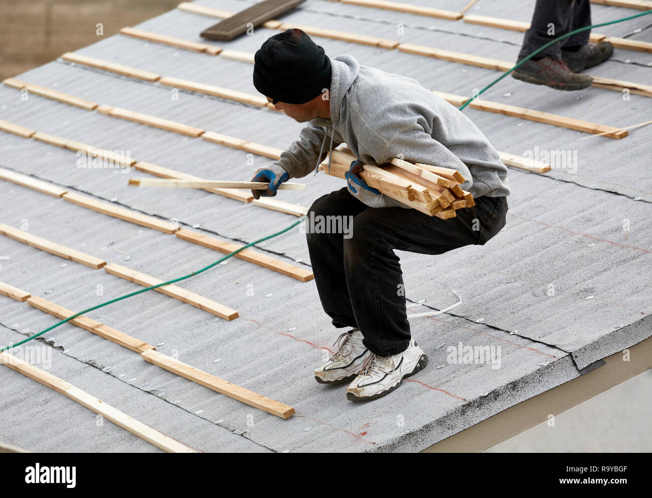 Man on roof laying wooden slats preparing to roof a building Stock ...