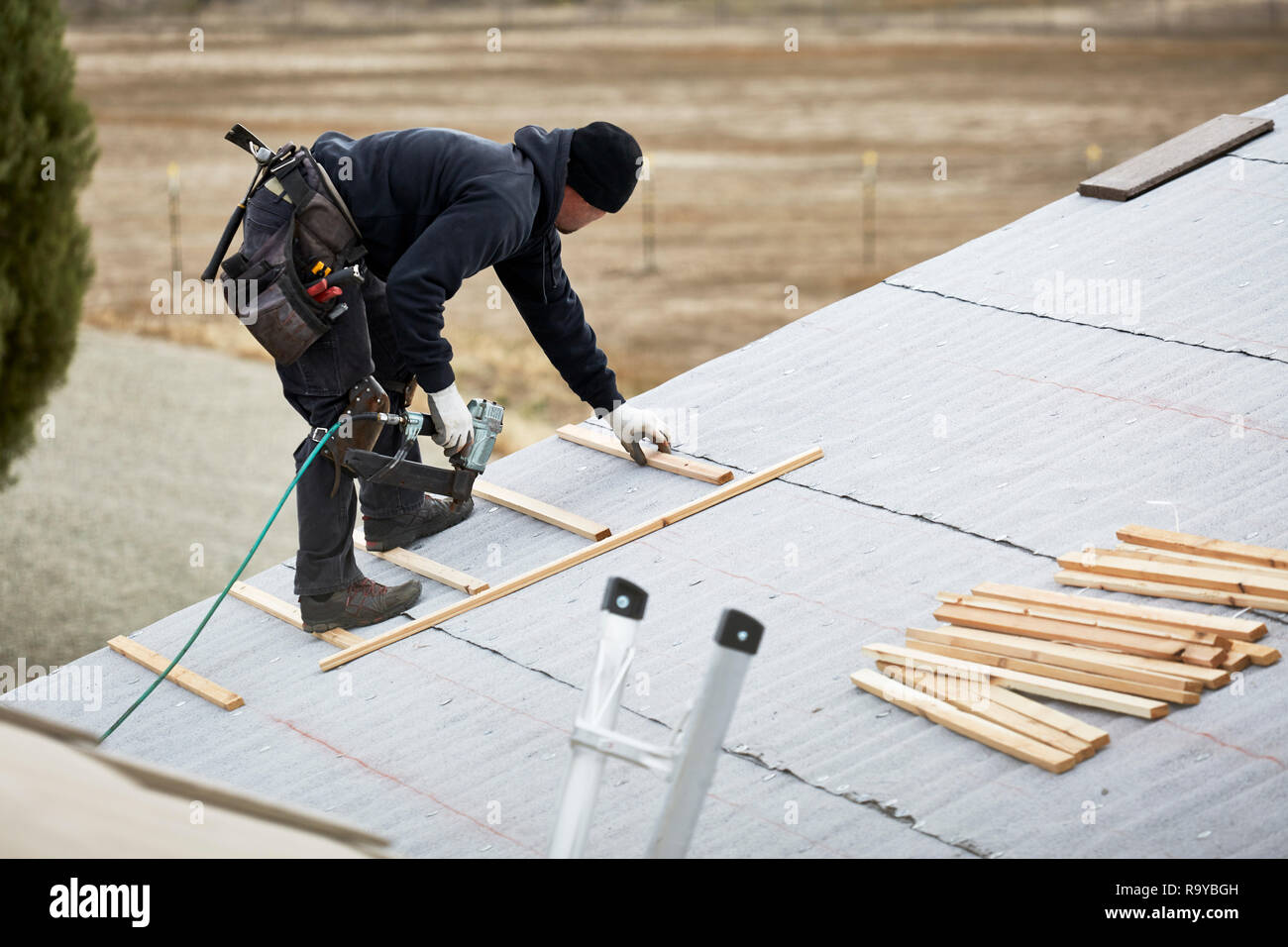 Man on roof laying wooden slats preparing to roof a building Stock ...