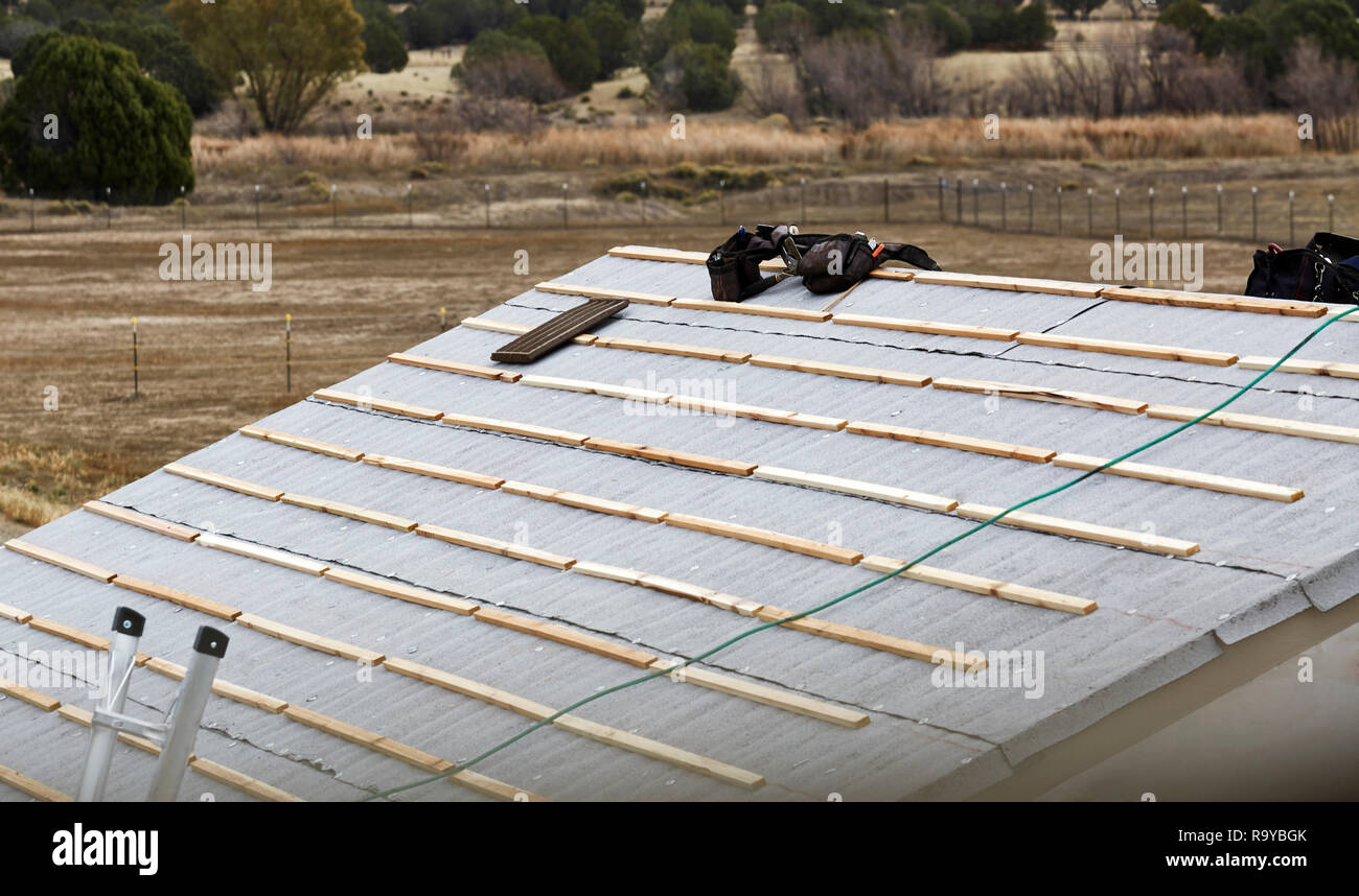 Wooden slats laying on rooftop with tool belt and clay tile in ...