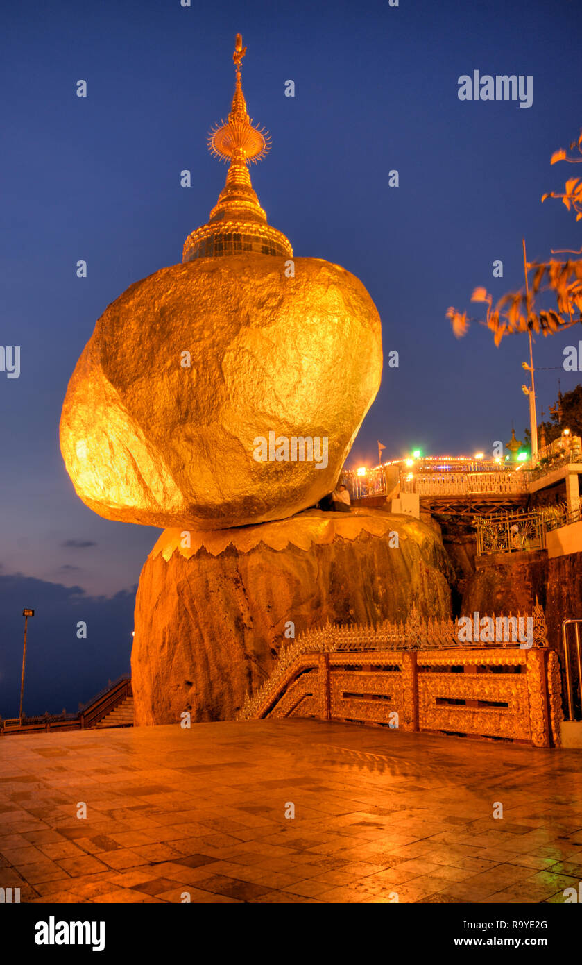 The illuminated Golden Rock of Kyaikhtiyo Pagoda during twilight ...