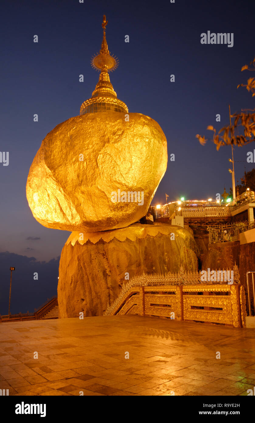 The illuminated Golden Rock of Kyaikhtiyo Pagoda during twilight ...