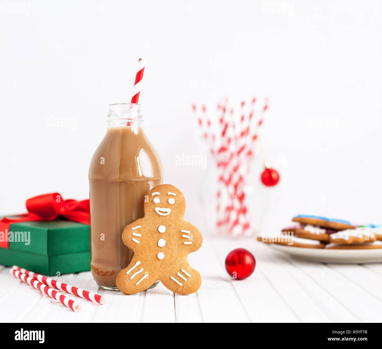 Gingerbread near bottle with chocolate milk and stripped straw on white ...