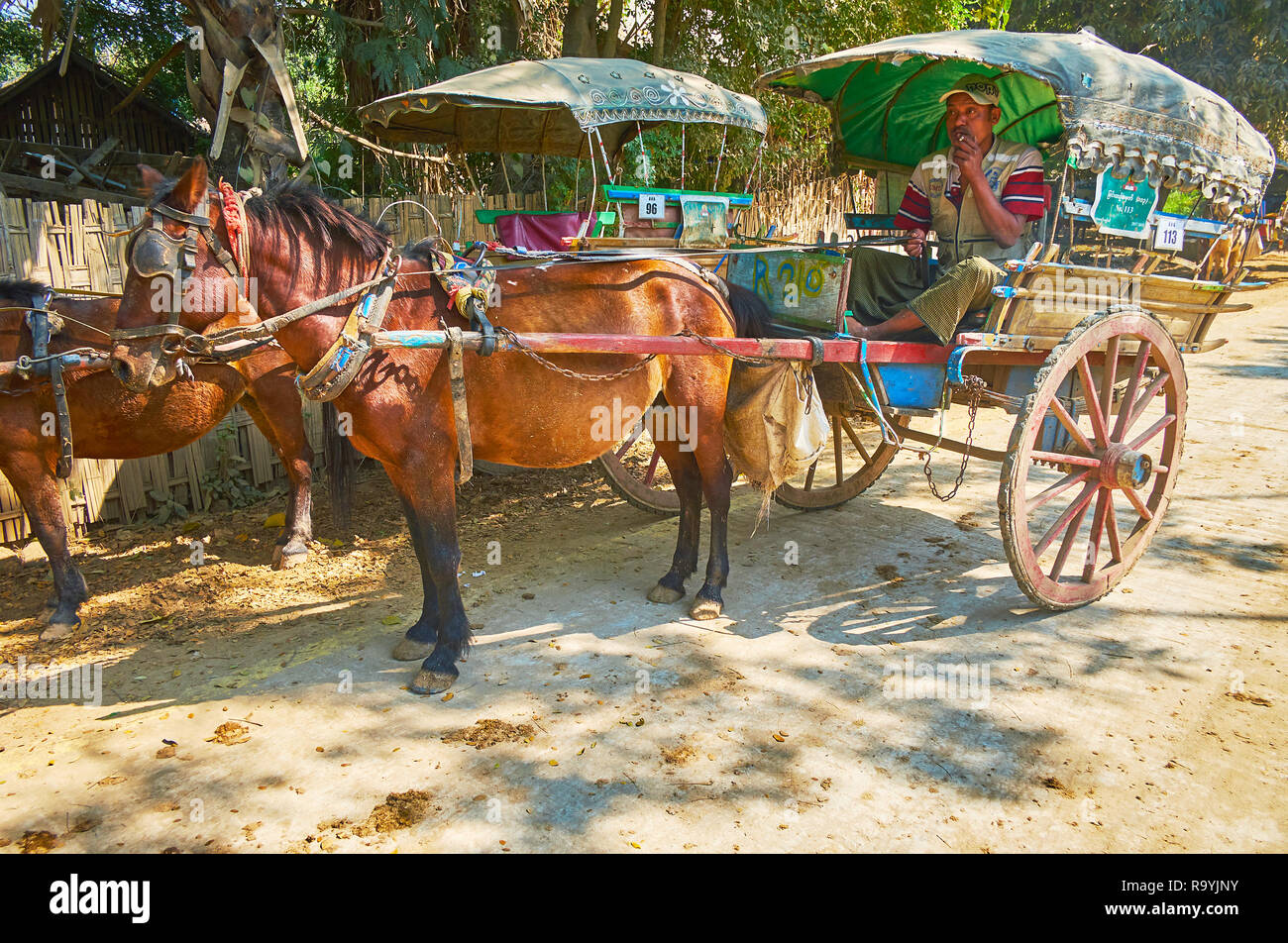 AVA, MYANMAR - FEBRUARY 21, 2018: The elderly coachman sits in shabby ...