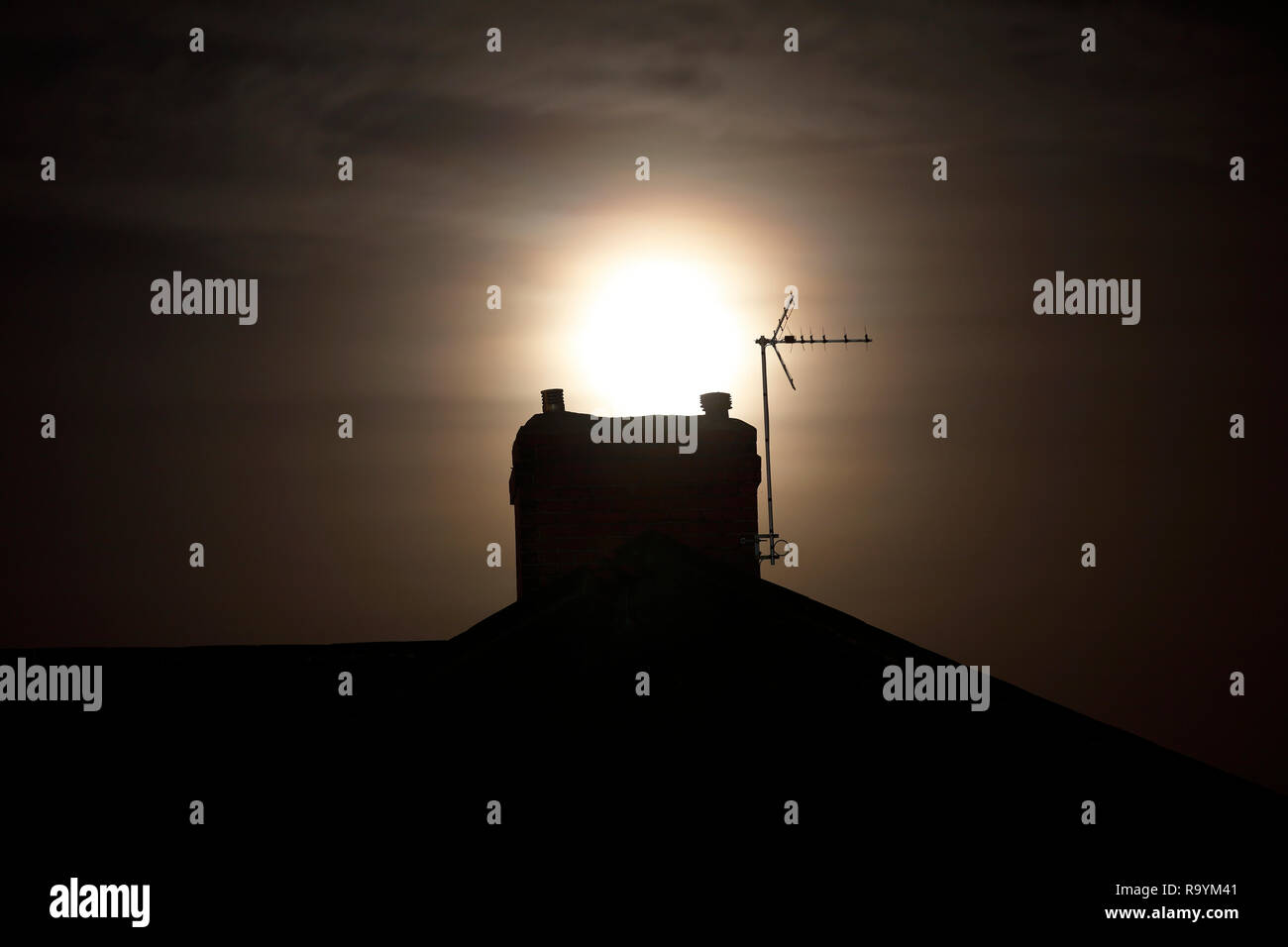 The moon behind a rooftop chimney Stock Photo - Alamy