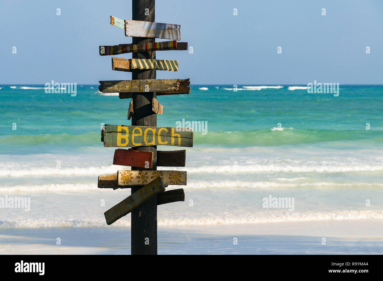 A signpost with Beach written on it with tropical beach and ocean in ...
