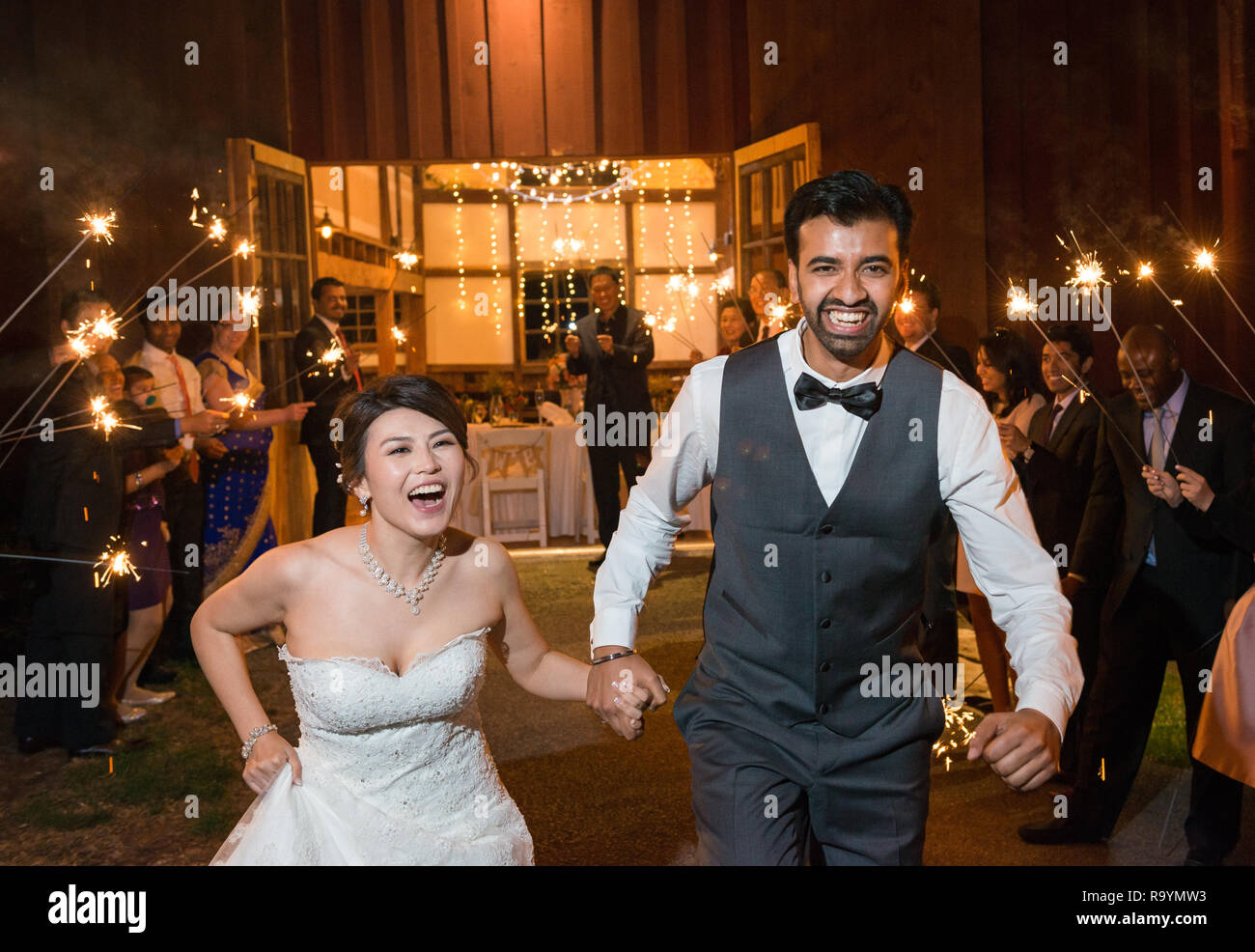 A bride and groom run off under a shower of sparkling lights during ...