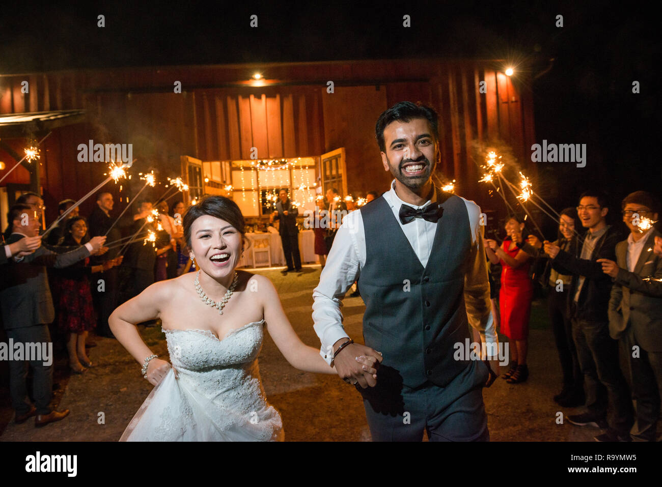 A bride and groom run off under a shower of sparkling lights during ...