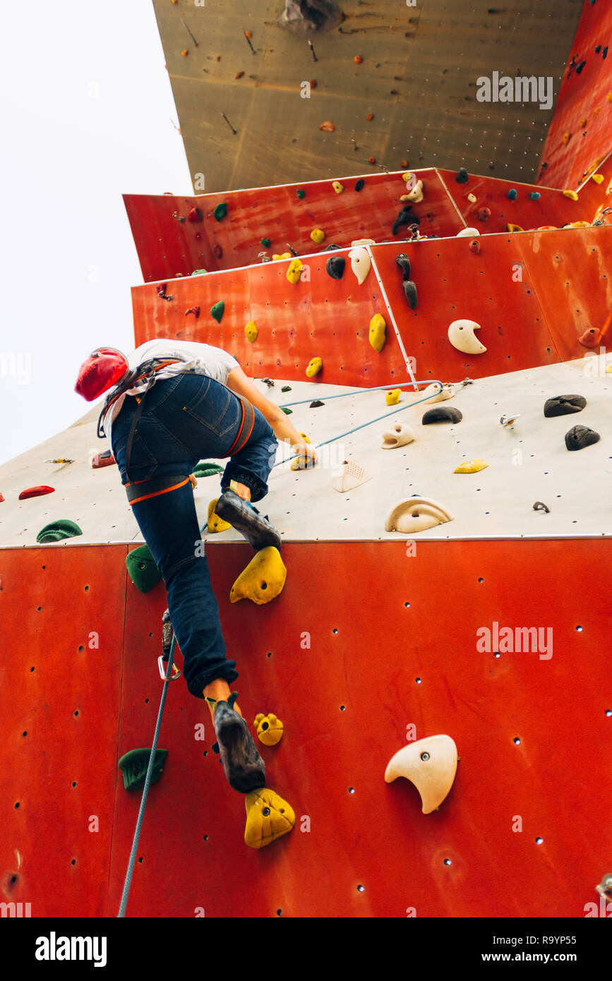Young climber guy climbing on practical rock in climbing center ...