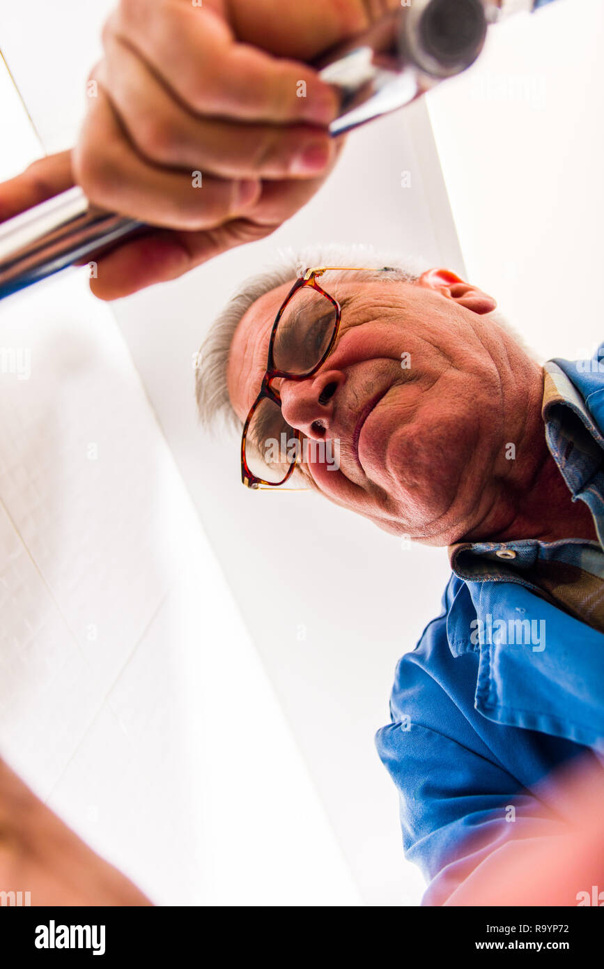Old age handyman holding his tool in the kitchen and working Stock ...