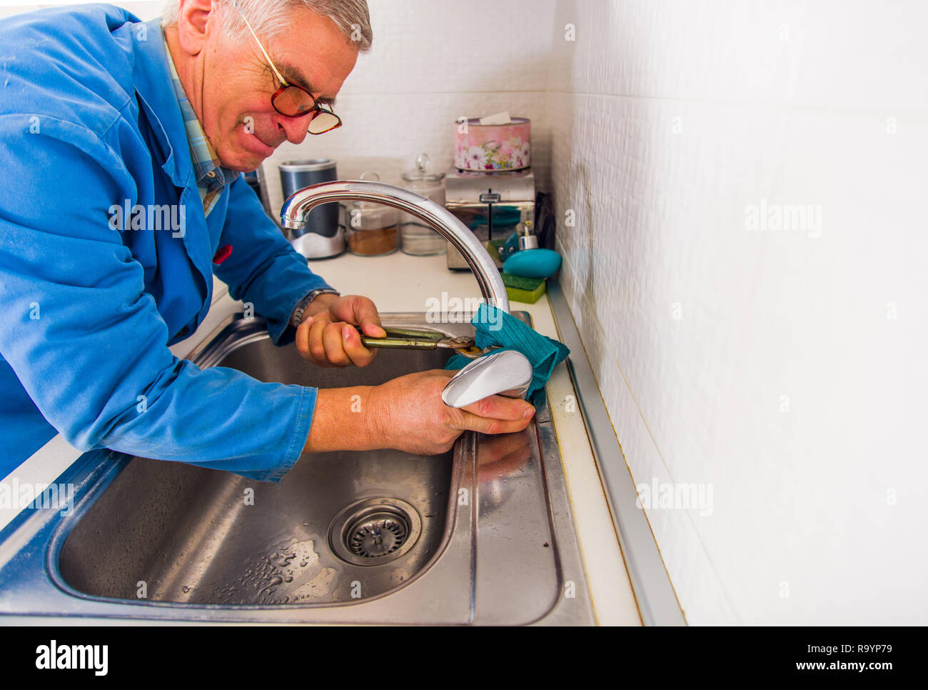 Old age handyman holding his tool in the kitchen and working Stock ...