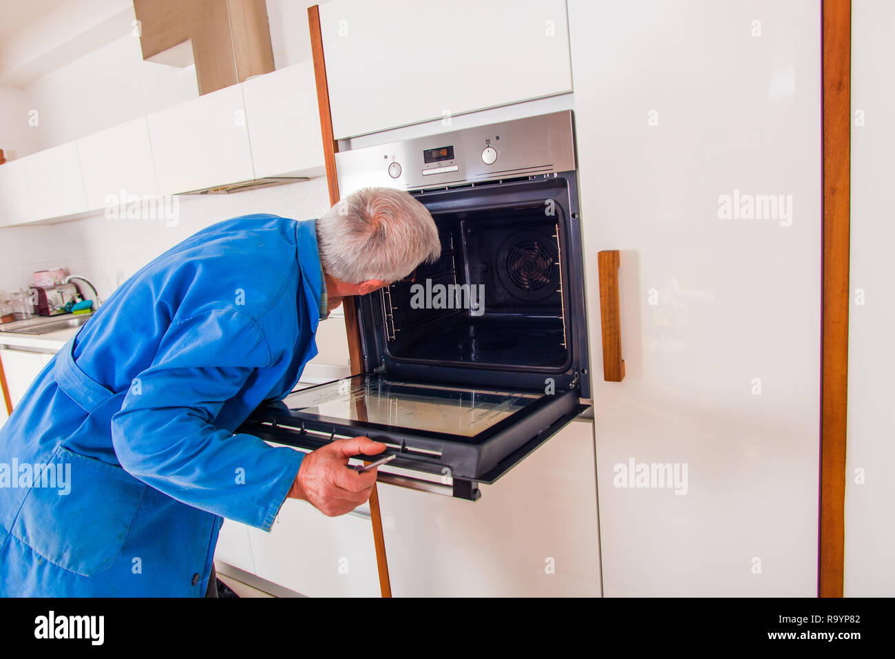 Service man working on oven in the kitchen Stock Photo - Alamy