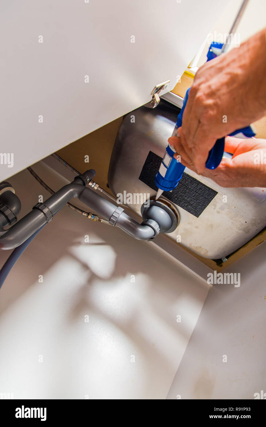 Professional handyman is working in the kitchen with caulking gun Stock ...