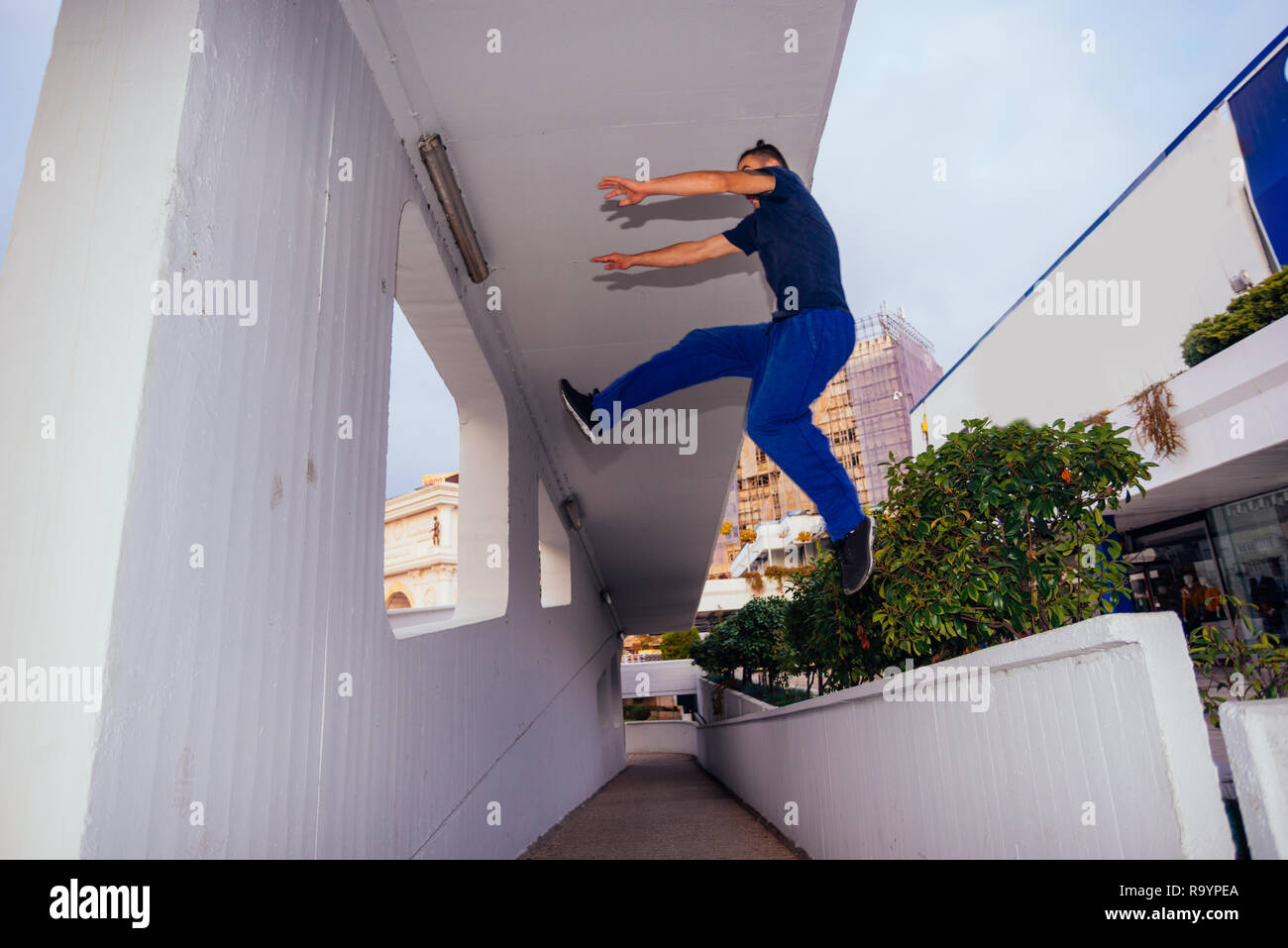 Young parkour man jumping from one to another wall while doing some ...