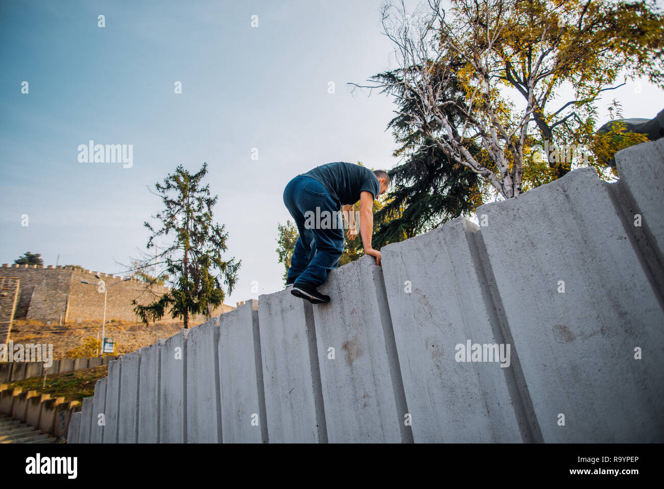 Traceur man hiking on the concrete obstacle while exercising parkour ...