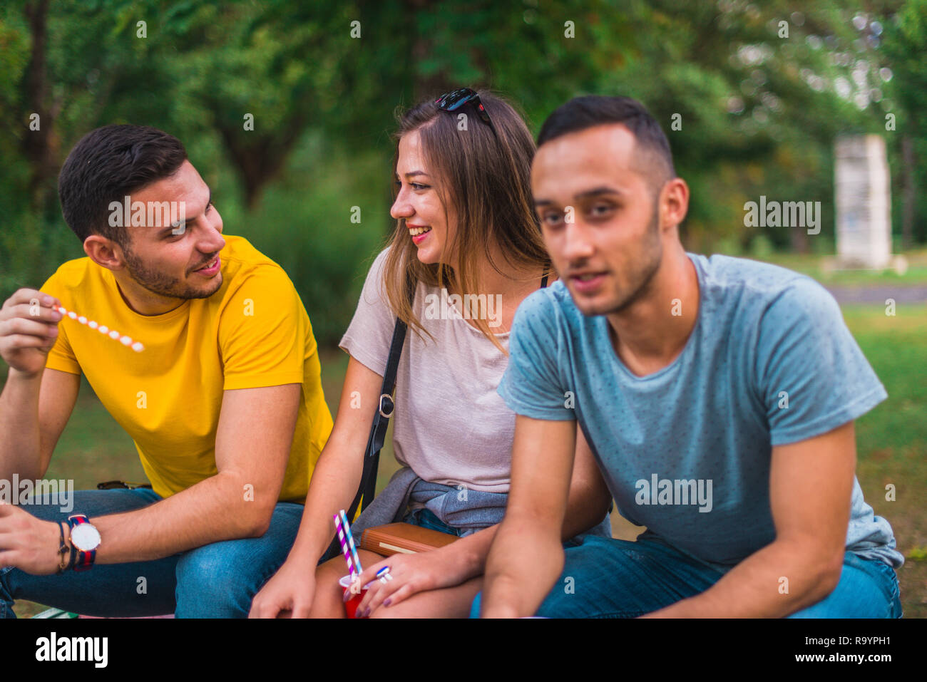 Friends are fooling around and smiling, sitting on a park bench Stock ...
