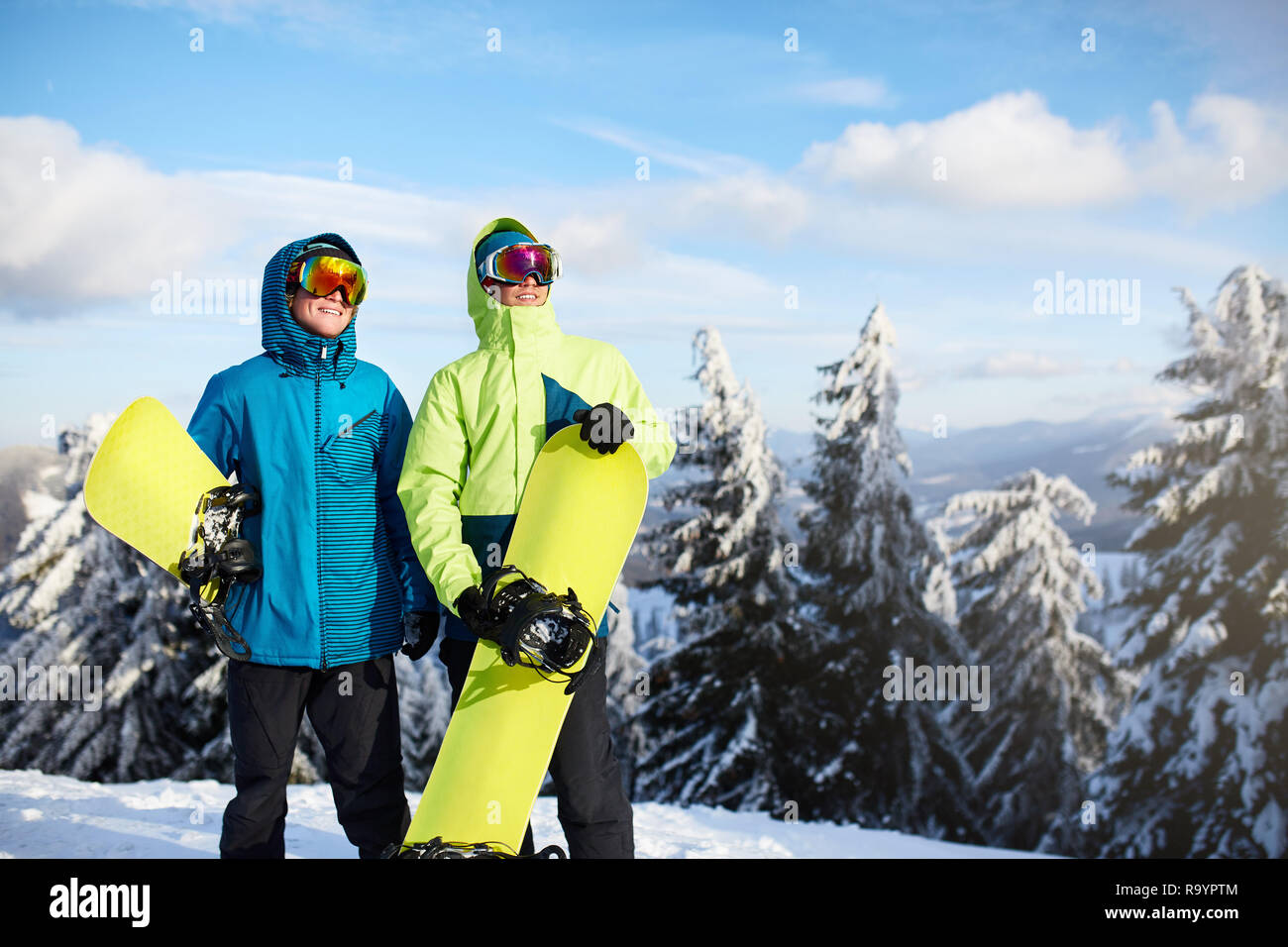 Two snowboarders posing at ski resort. Riders friends carrying their ...