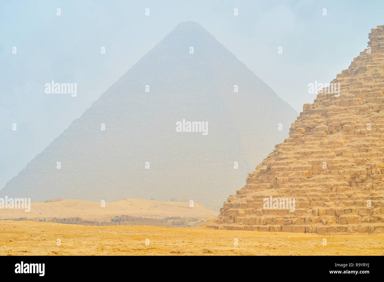 The scenic view on Giza's pyramids through the morning heavy fog and ...