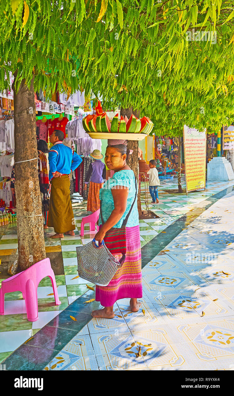 SAGAING, MYANMAR - FEBRUARY 21, 2018: The young woman sells the slices ...