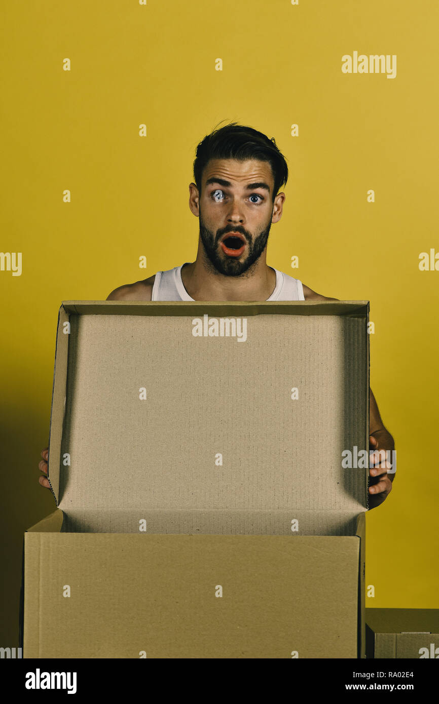 Man holding empty cardboard box. Guy with carton on yellow background ...