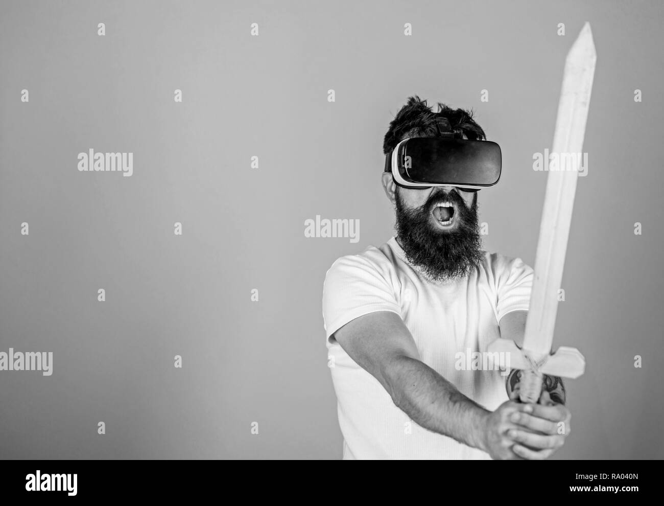 VR gamer concept. Guy with head mounted display and sword play fighting ...