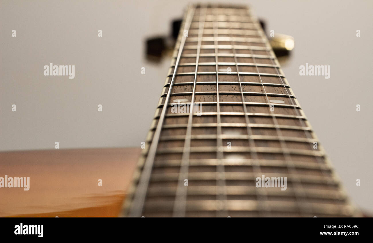 Musical instrument at an angle with blur of strings and fretboard on ...