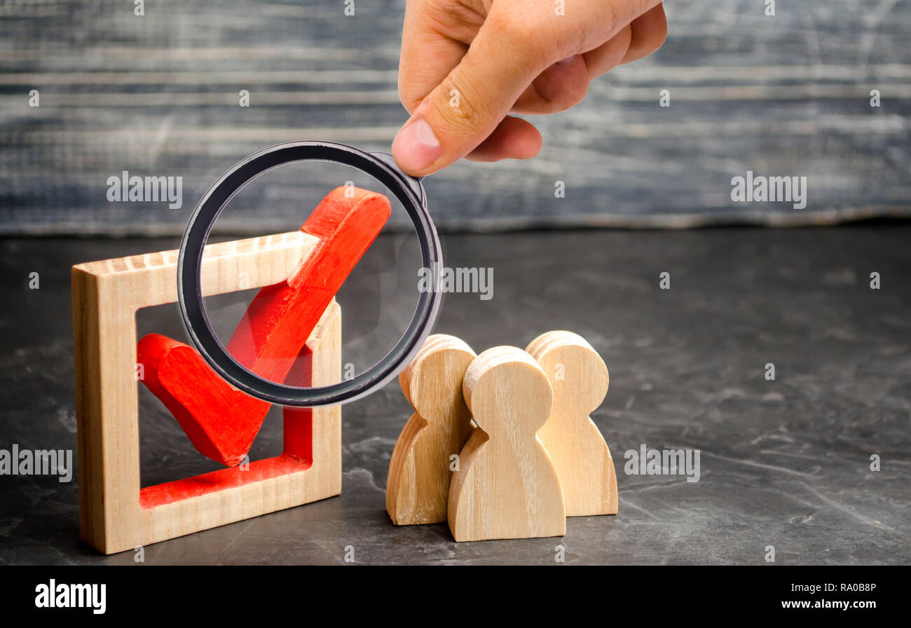 Wooden human figures stand together next to a tick in the box. The ...
