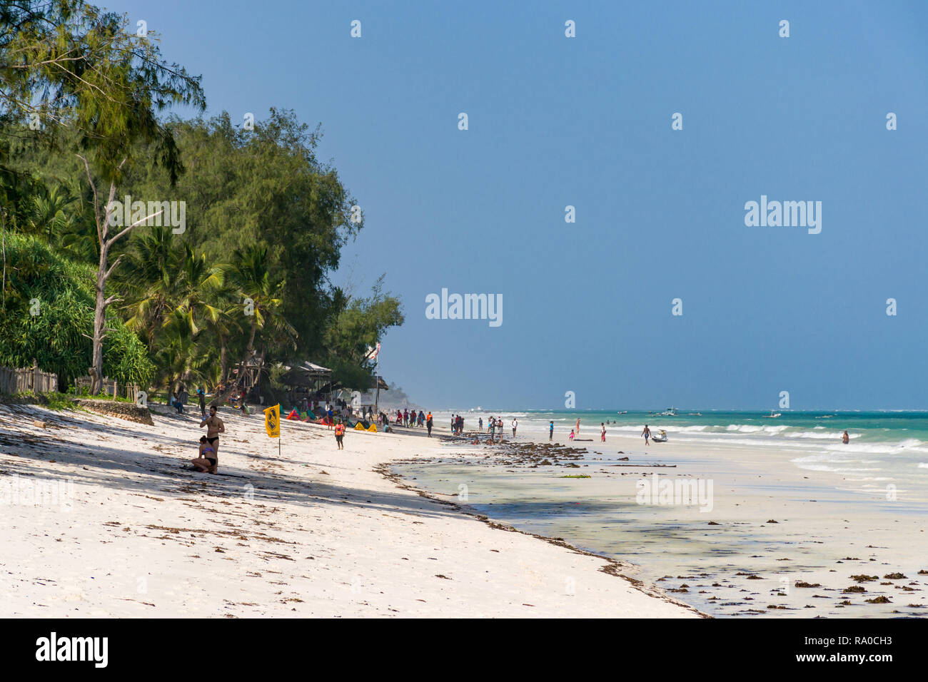 Tourists on the tropical white sand beach of Diani at low tide on a ...