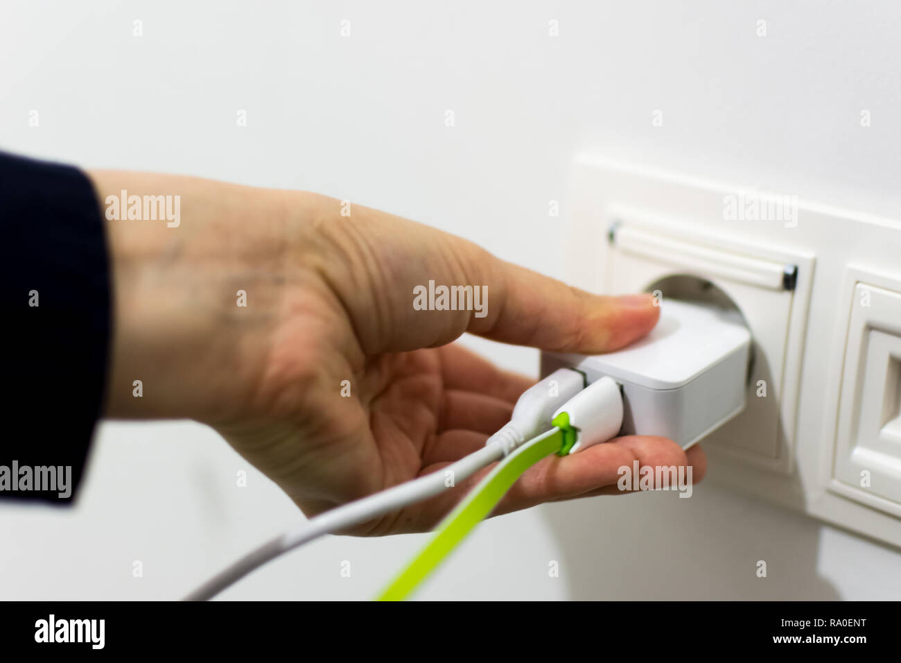 Charger with two cables in the socket and female hand holding it ...