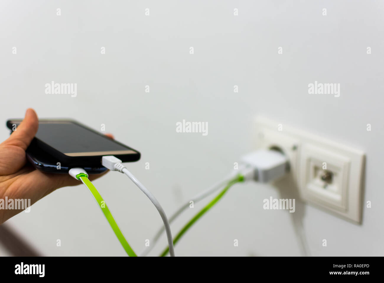 Two mobile phones charging plugged into the charger Stock Photo - Alamy