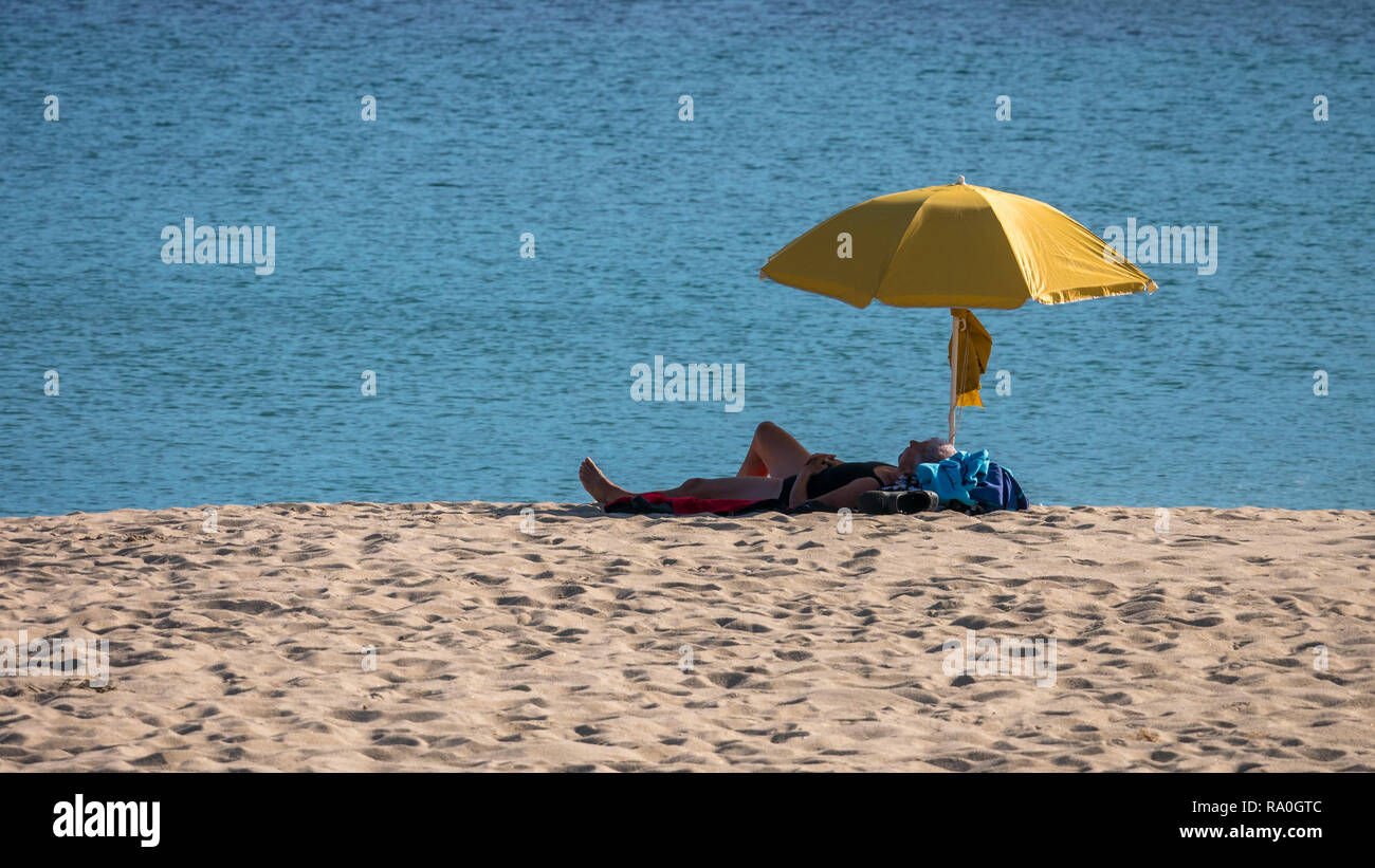 An elderly woman during good weather at end of summer taking a nap ...