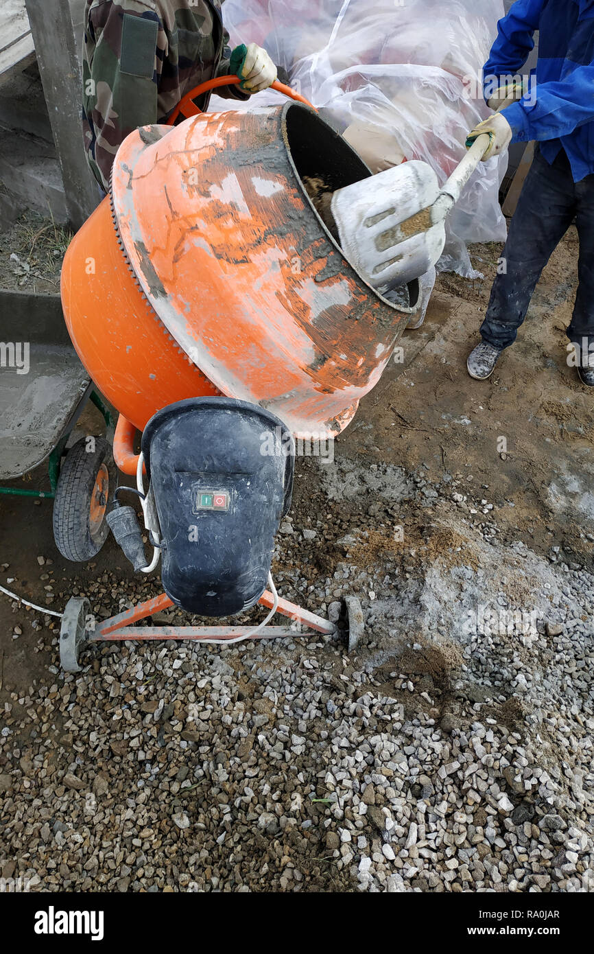 auxiliary worker develops a cement mortar in a concrete mixer at the ...