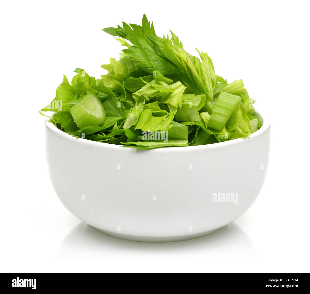 Fresh celery stalks chopped in a white bowl isolated on white ...