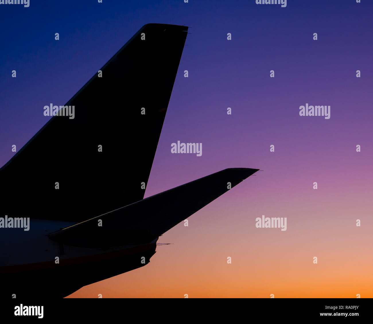 Plane tail with sunset colours in background Stock Photo - Alamy