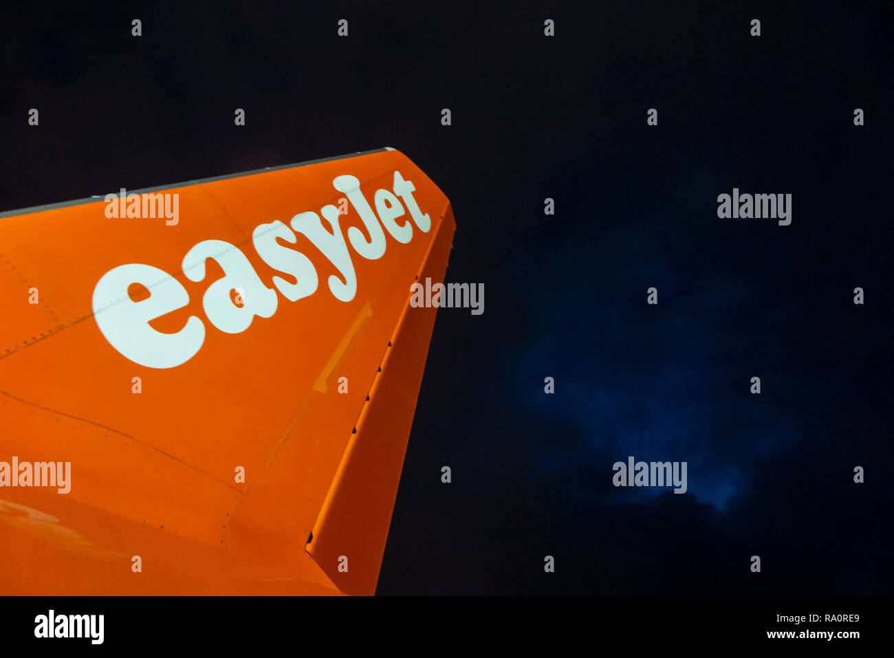 An Easyjet tailplane on the runway at night with a stormy sky above ...