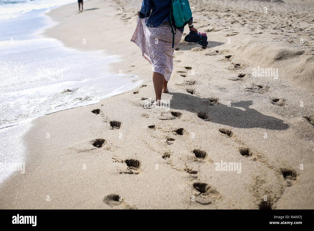 Lonely woman on the beach leaving foot imprints in the sand Stock Photo ...