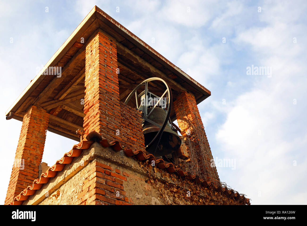 ancient medieval brick bell tower with bronze bell and blue sky with ...