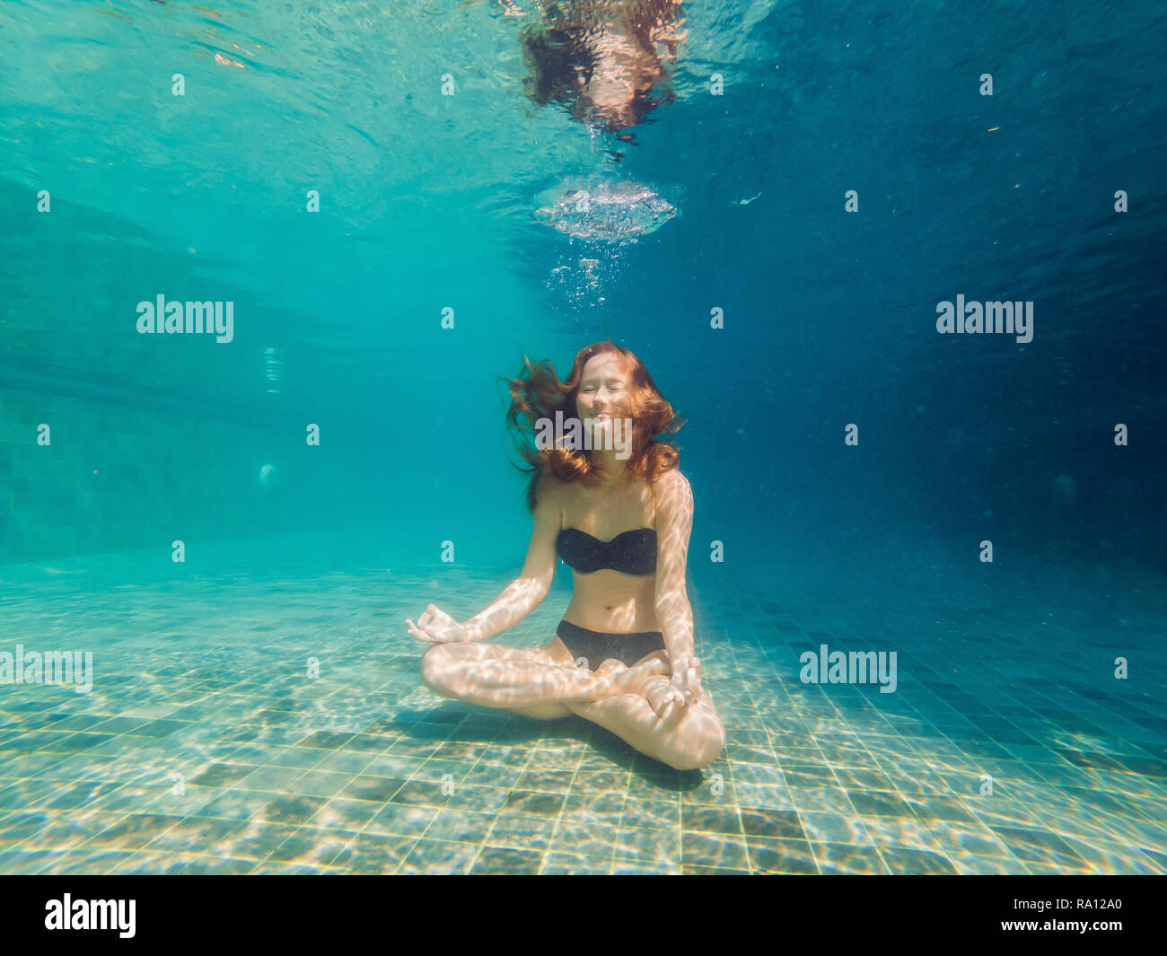 Young Woman In Black Bikini In Yoga Position Underwater In Diving