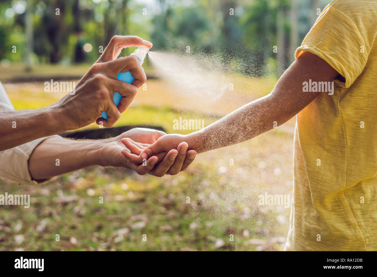 dad and son use mosquito spray.Spraying insect repellent on skin ...