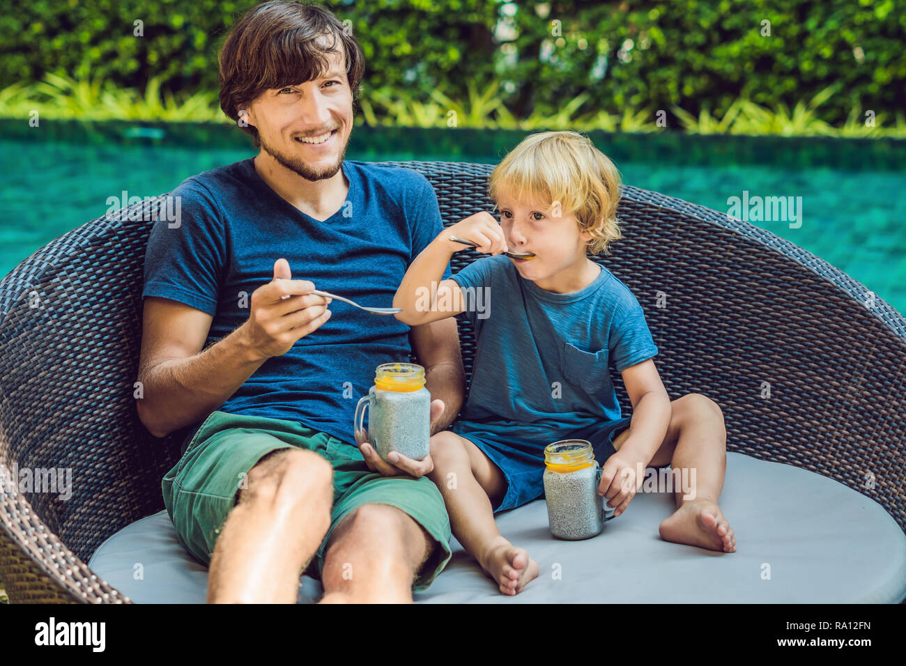 Father and son eat dessert with chia seeds and mangoes by the pool in ...